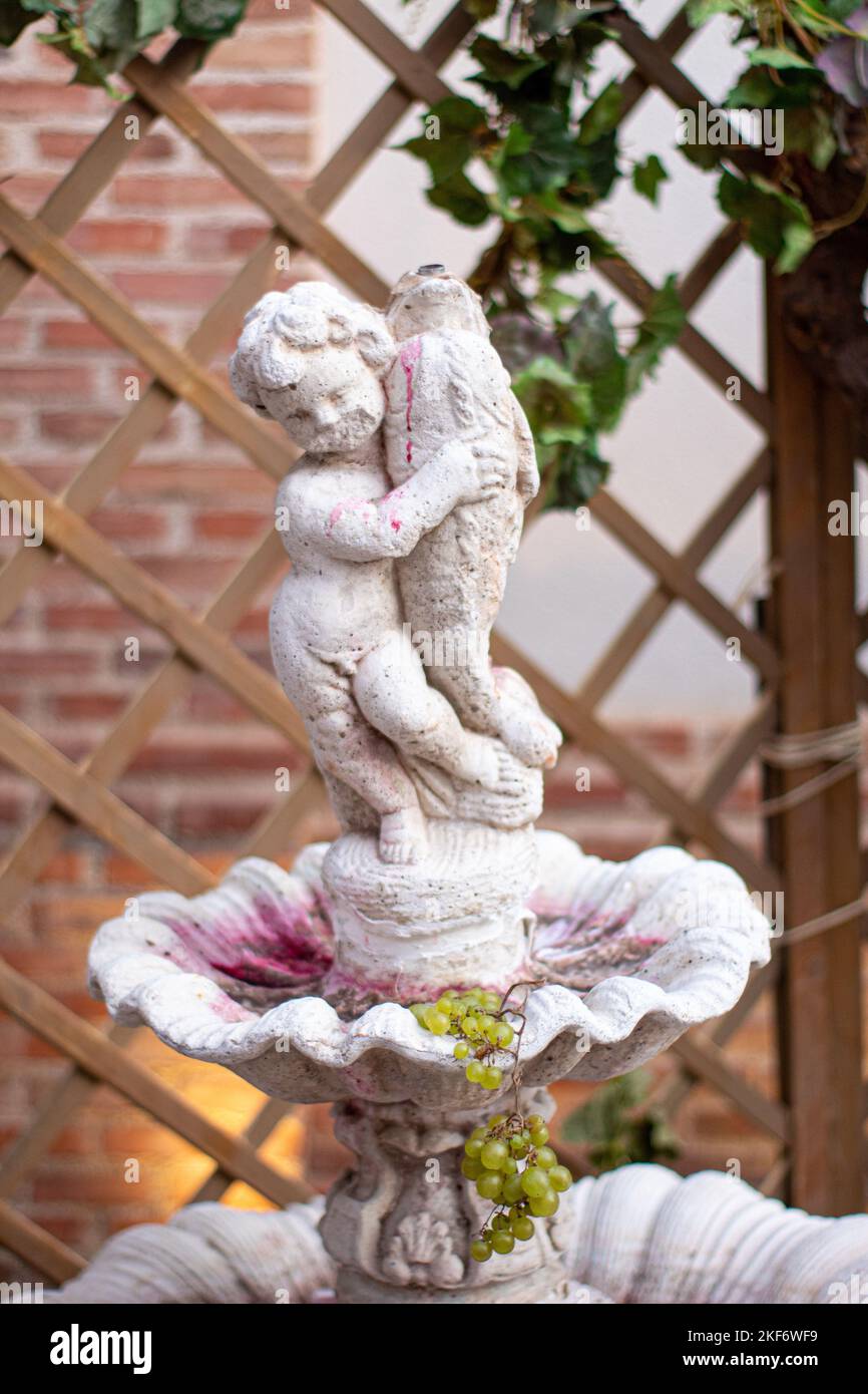 The vertical view of a dirty fountain statue of a boy hugging the fish ...