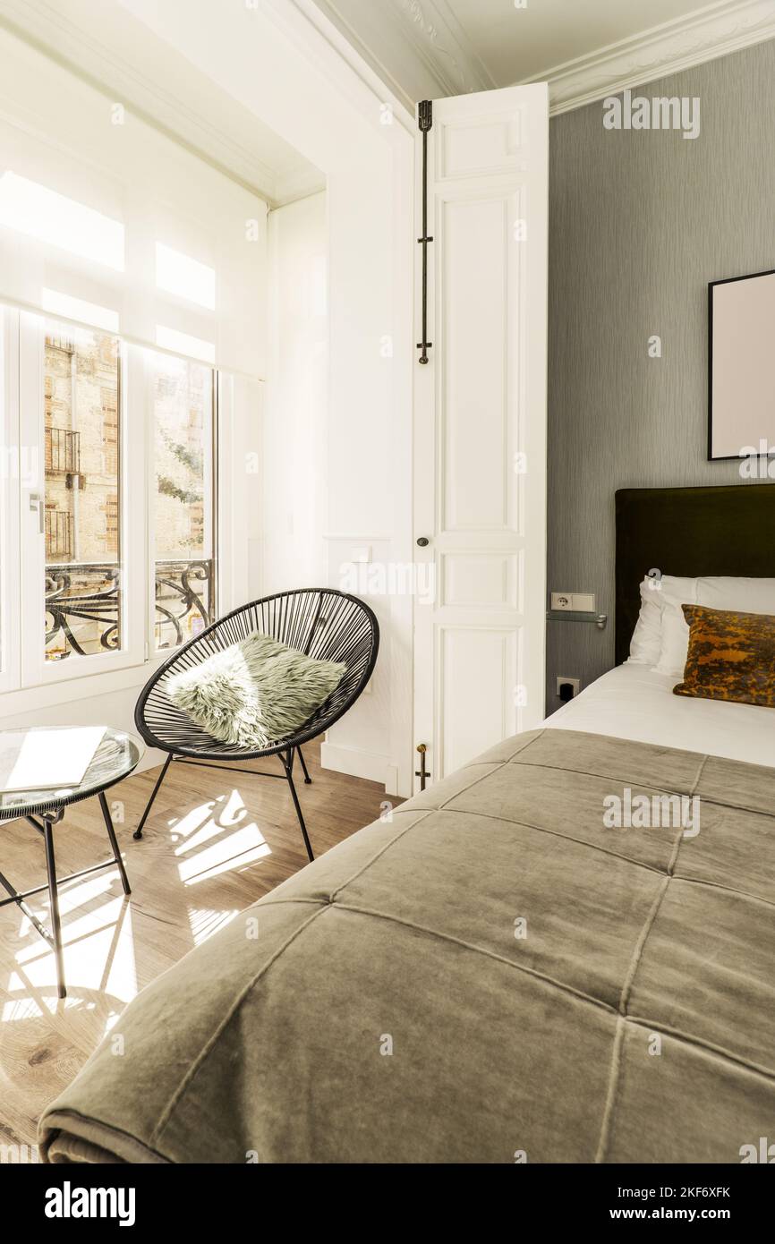 Corner of a bedroom with an upholstered headboard and a balcony with ...