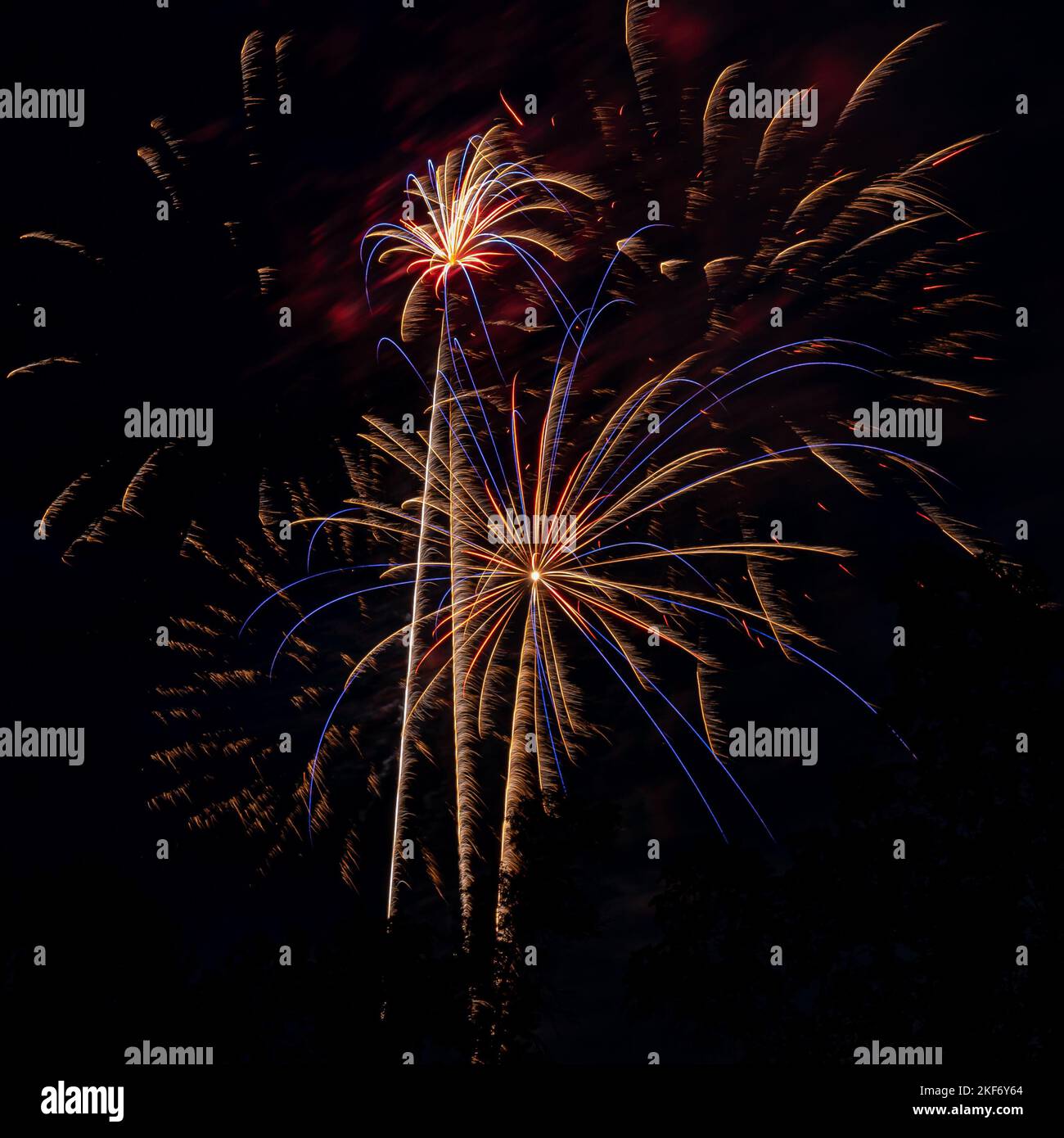 Two large exploding fireworks and a streak of a third one, isolated on ...