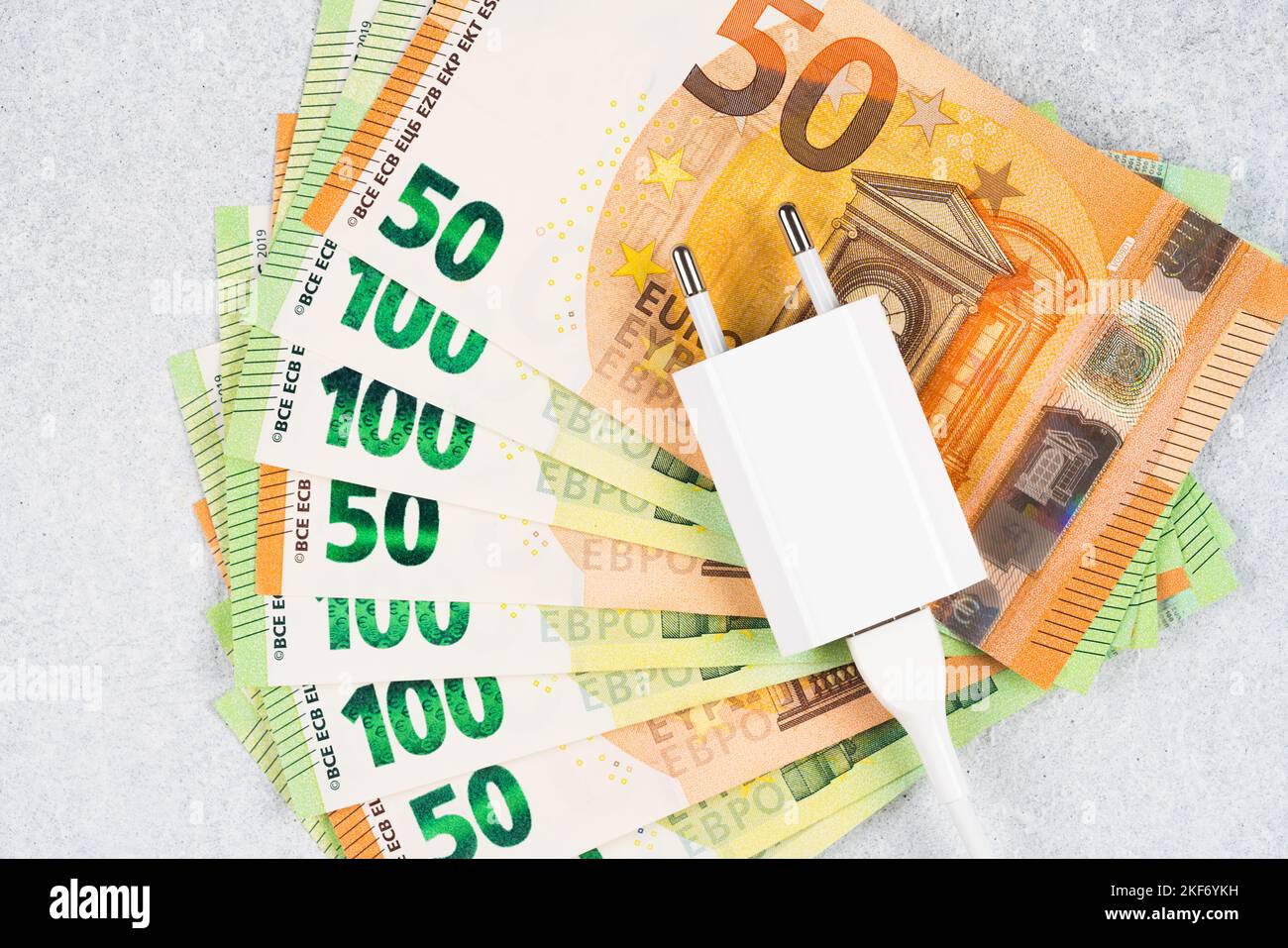 White charger plug with many euro banknotes over light concrete ...