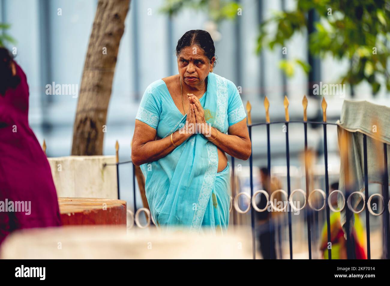A woman in blue praying to idols and guards at the Narasimha Hindu ...