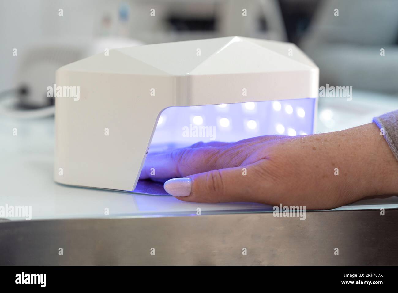 A hand of an older woman drying her nails in an ultraviolet lamp Stock ...