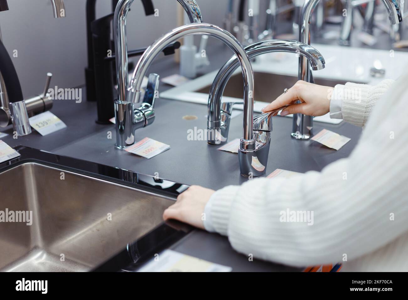 Pretty young woman choosing a bathroom/kitchen tap in a home ...