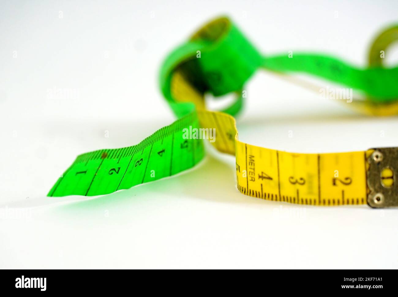 yellow and green tape measure on white background Stock Photo - Alamy