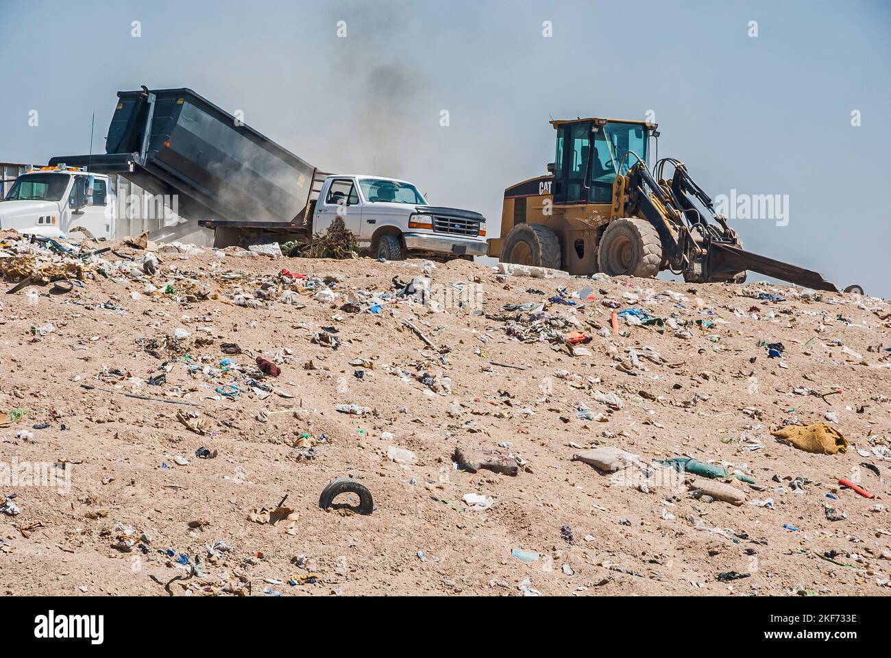 A flat-bed truck, a dump truck, and a soil compactor / tractor at an ...