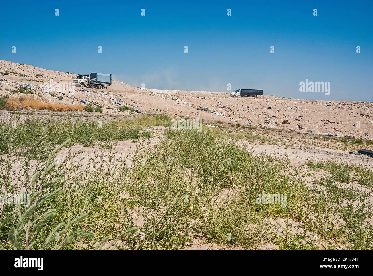 One dump truck follows another at the crest of a hillside in an active ...