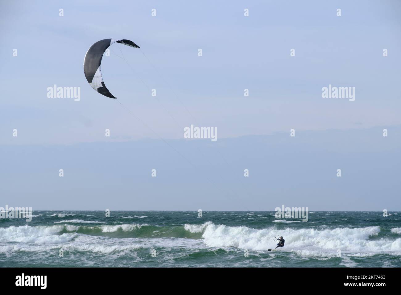 Kitesurfing, riding board waves during storm holding to flying kite ...