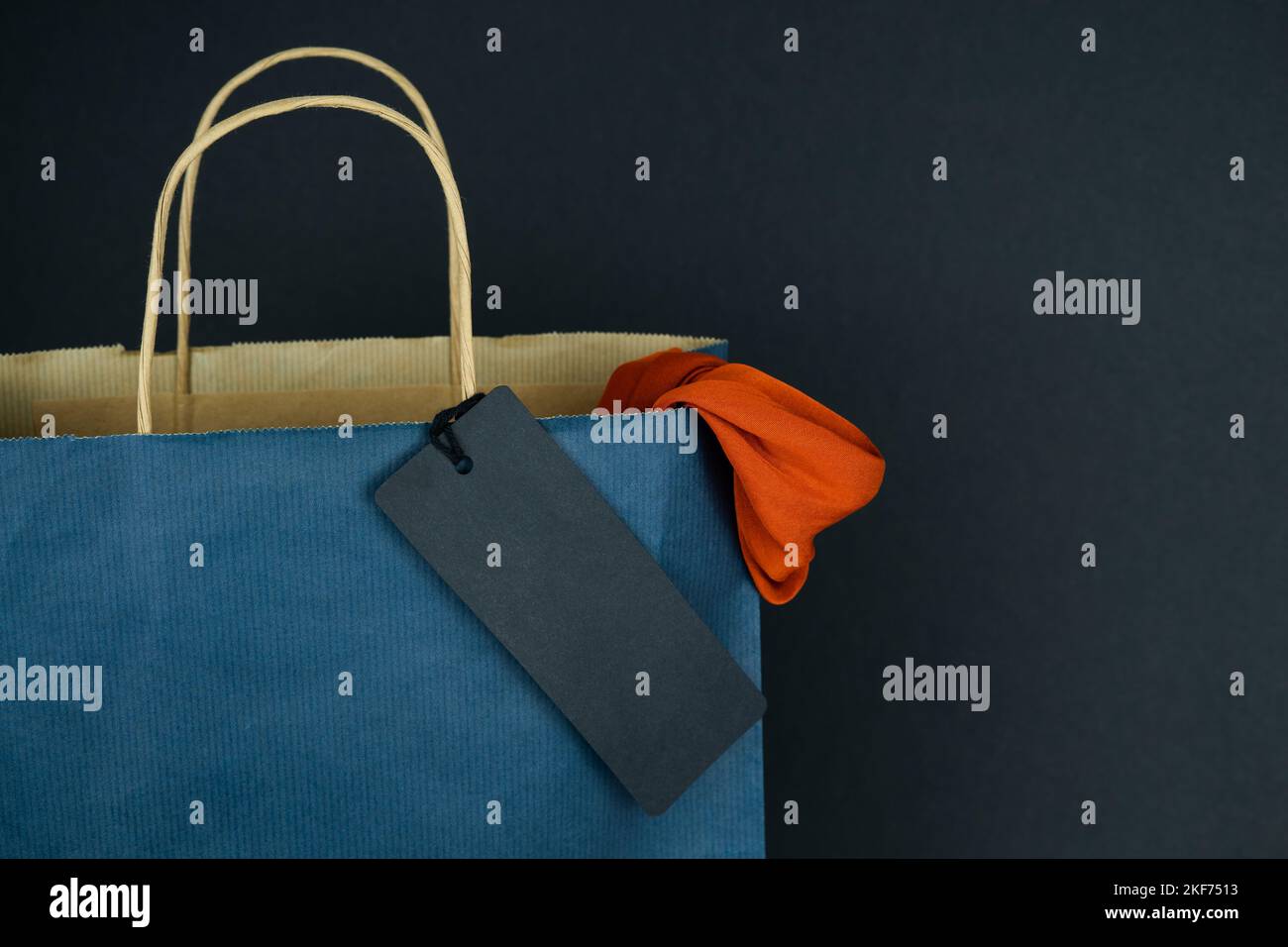 Blue paper bag with black label without text on dark background. Copy ...