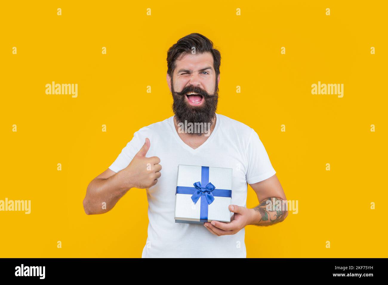 winking man with present isolated on yellow background. present box for ...