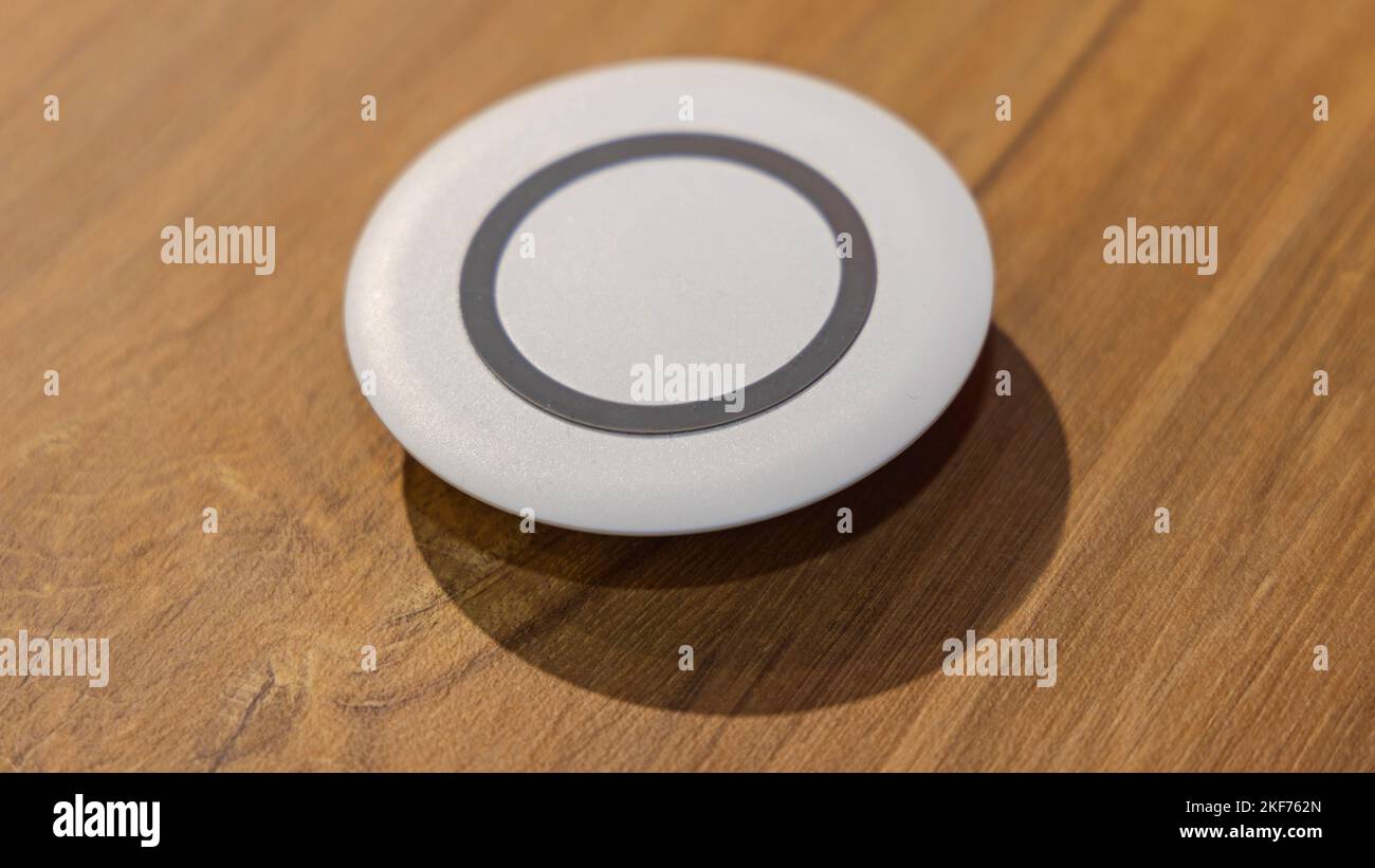 White Round Wireless Charging Pad at Wooden Desk Stock Photo - Alamy