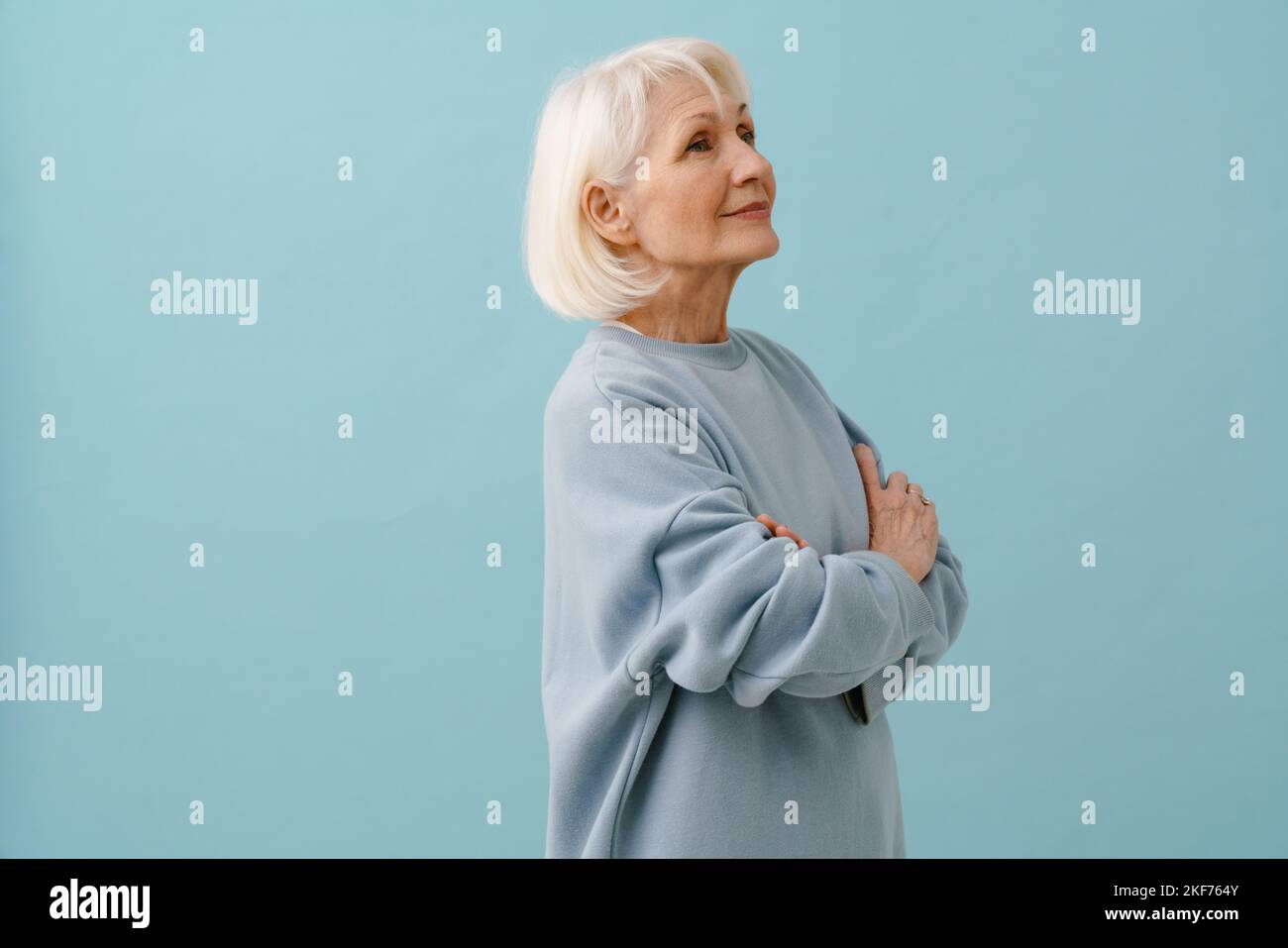 Beautiful senior woman in blue pullover standing with her right side ...