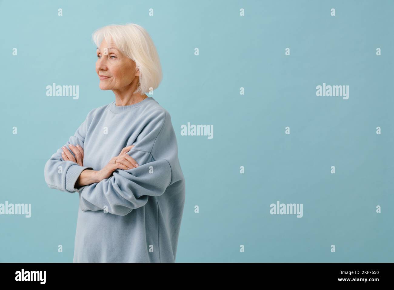 Beautiful senior woman in blue pullover standing with her left side ...