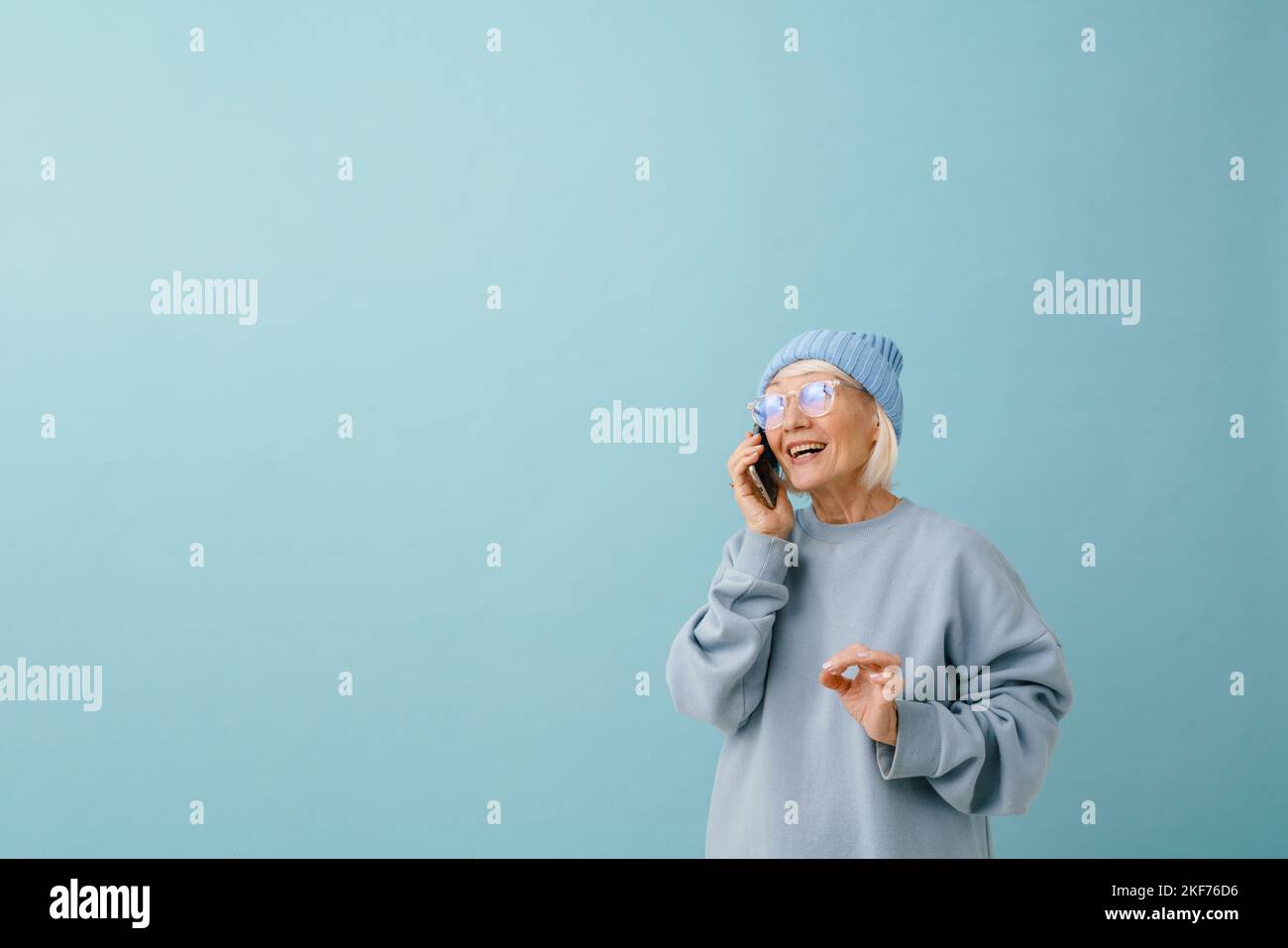 Beautiful smiling senior woman in winter hat and glasses talking on the ...
