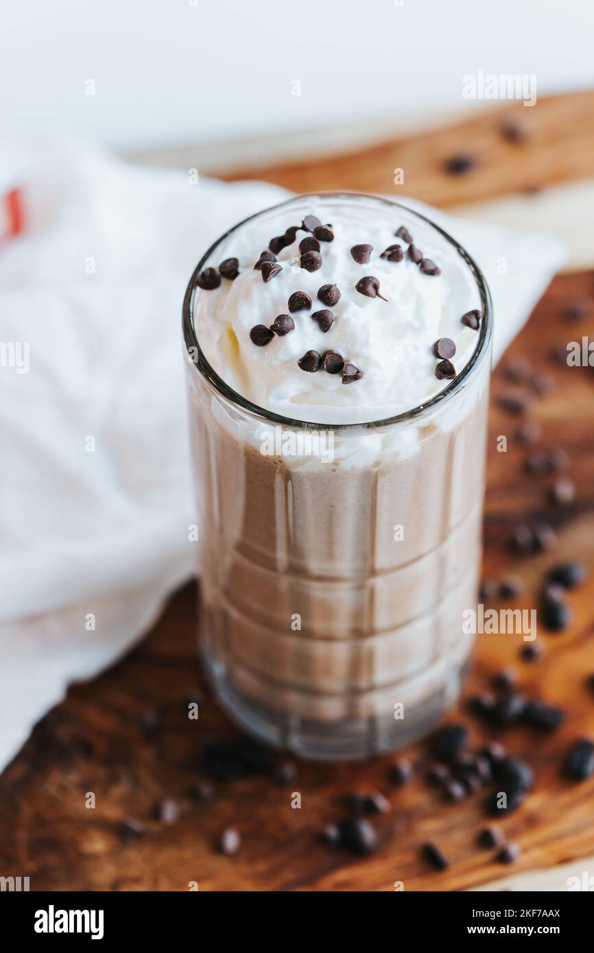 A vertical closeup of milkshake on the wooden table coffee beans and a ...