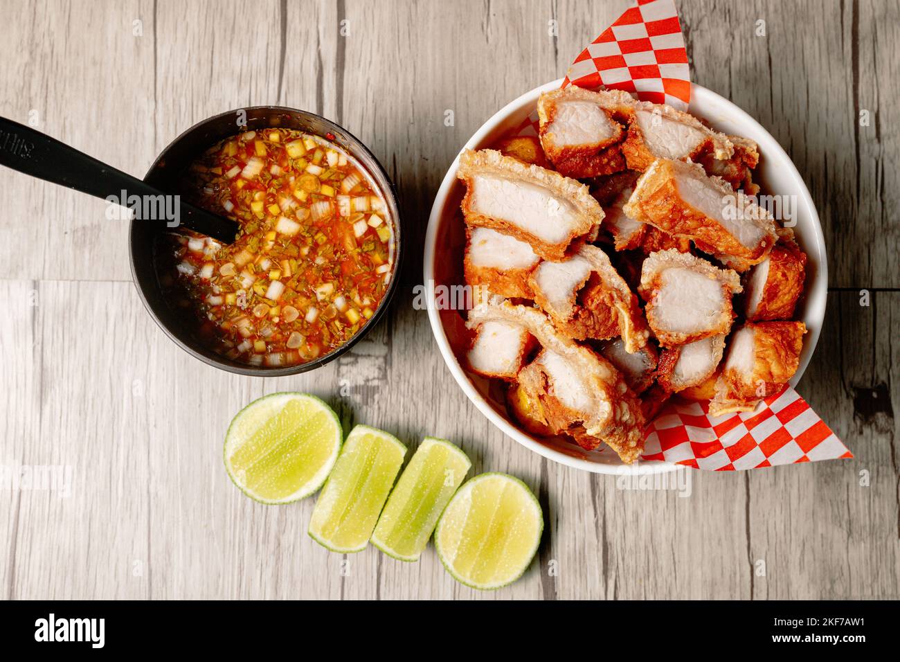A top view of Lechon kawali pork belly slabs and a bowl of vegetable ...