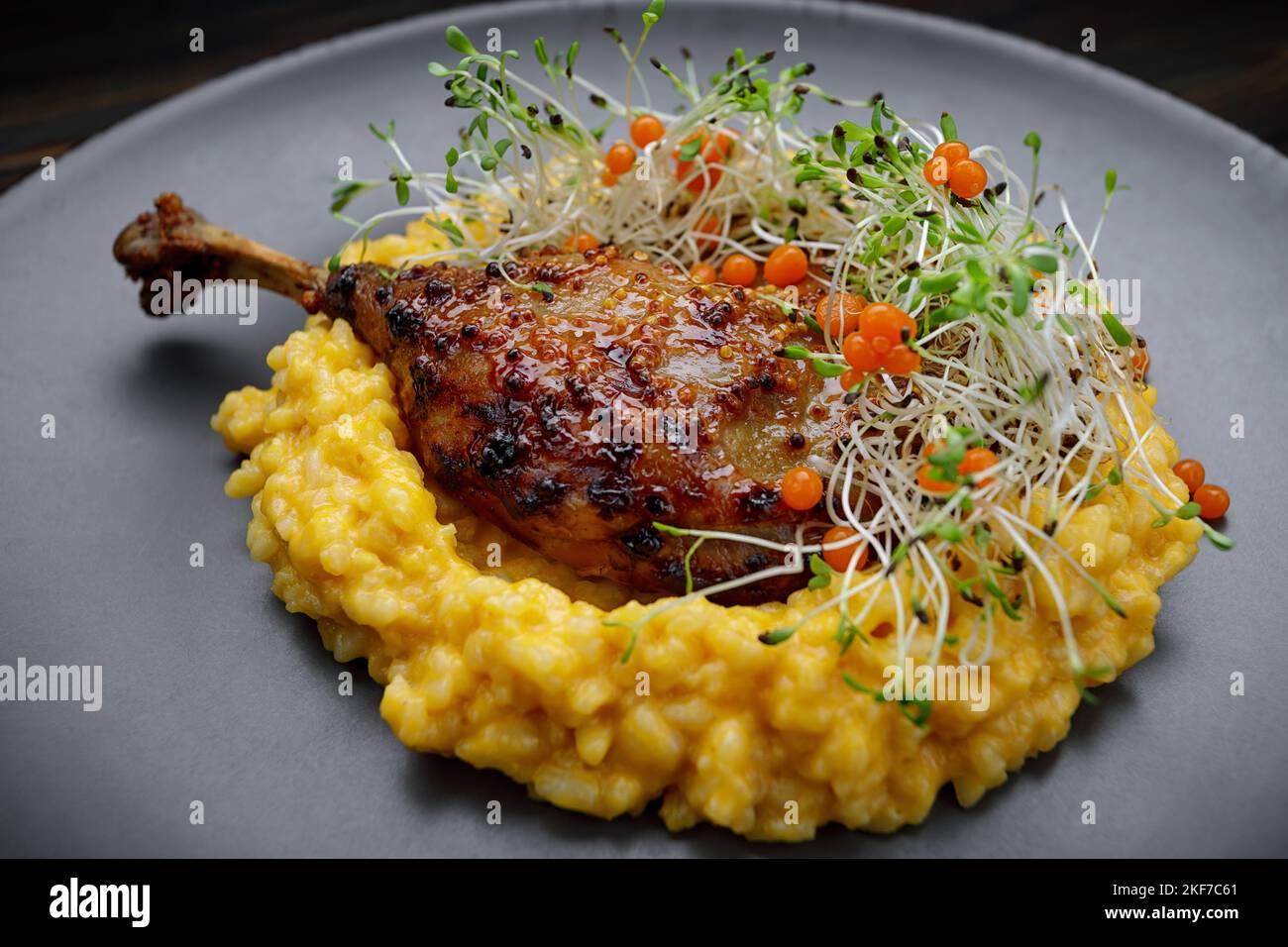 Duck leg with risotto, pumpkin and herbs on a dark background Stock ...
