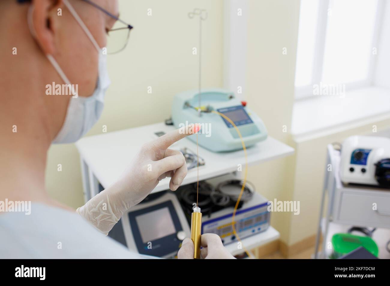 a male surgeon in the operating room sets up laser medical equipment ...