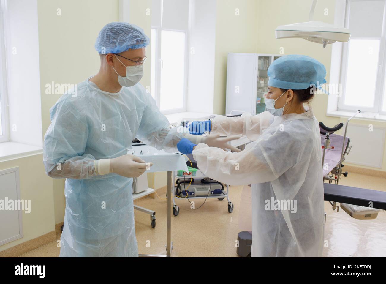The surgeon is preparing for surgery. An assistant helps an experienced ...