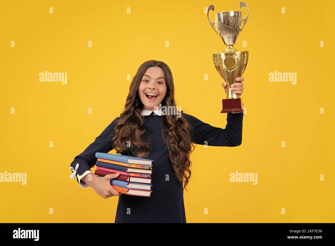 Excited schoolgirl in school uniform celebrating victory with trophy ...