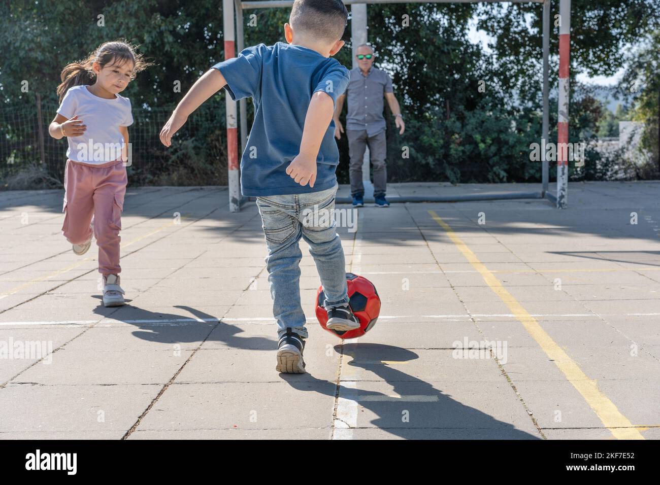 Happy family playing football. Back view of boy kicking soccer ball ...