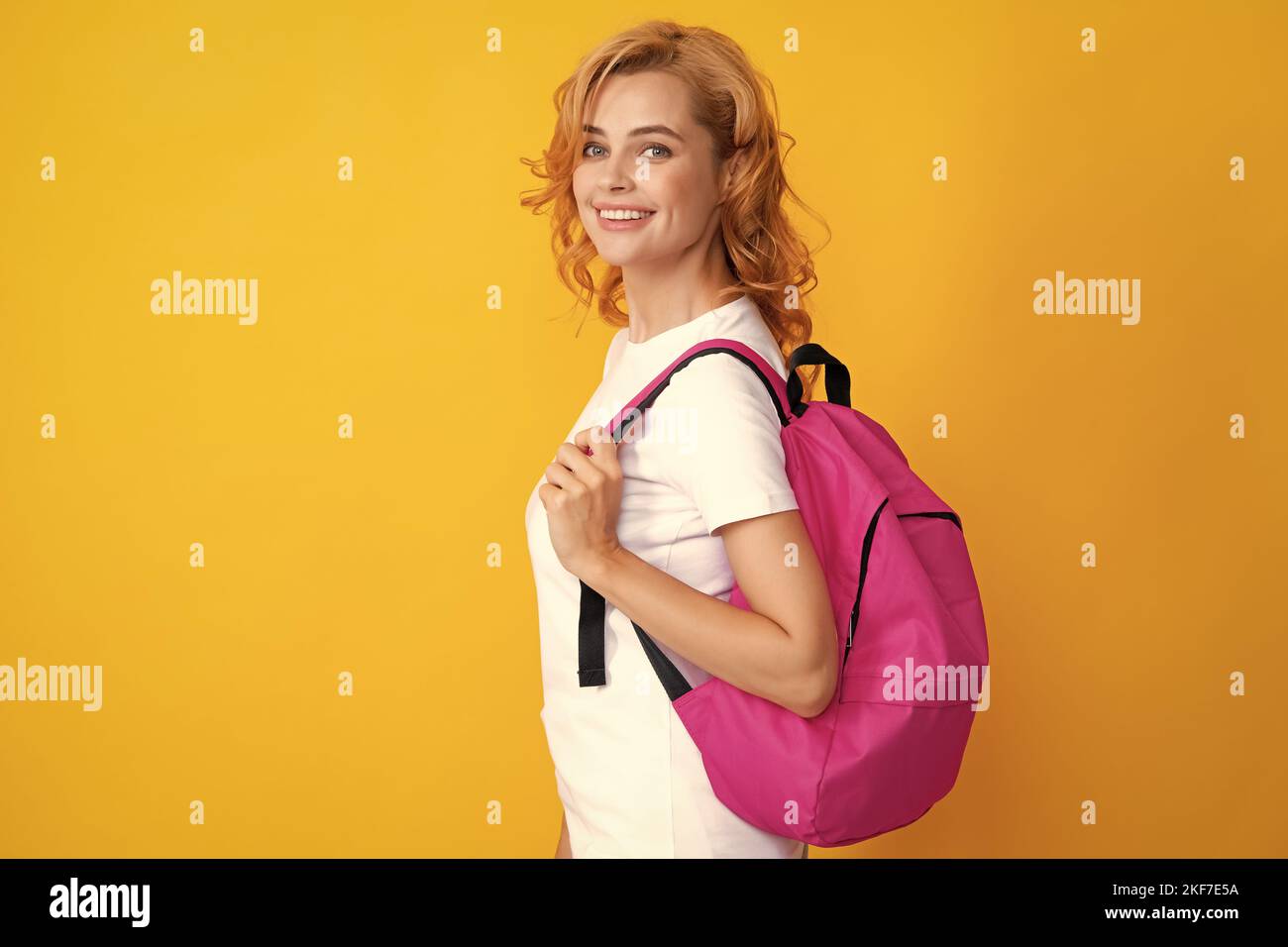 Excited redhead young woman student with backpack, isolated on yellow ...