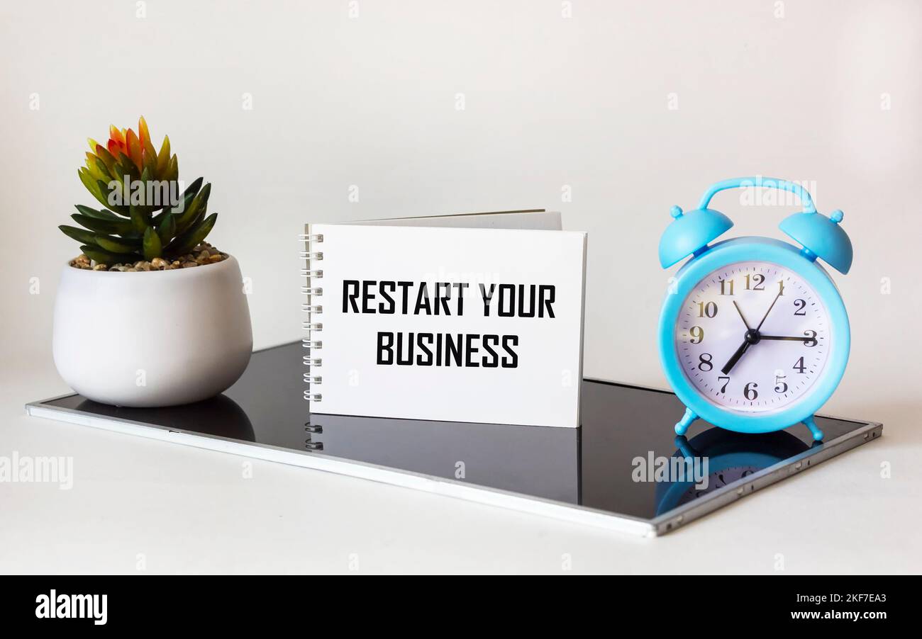 text in notepad Restart Your Business. White background with clock and ...