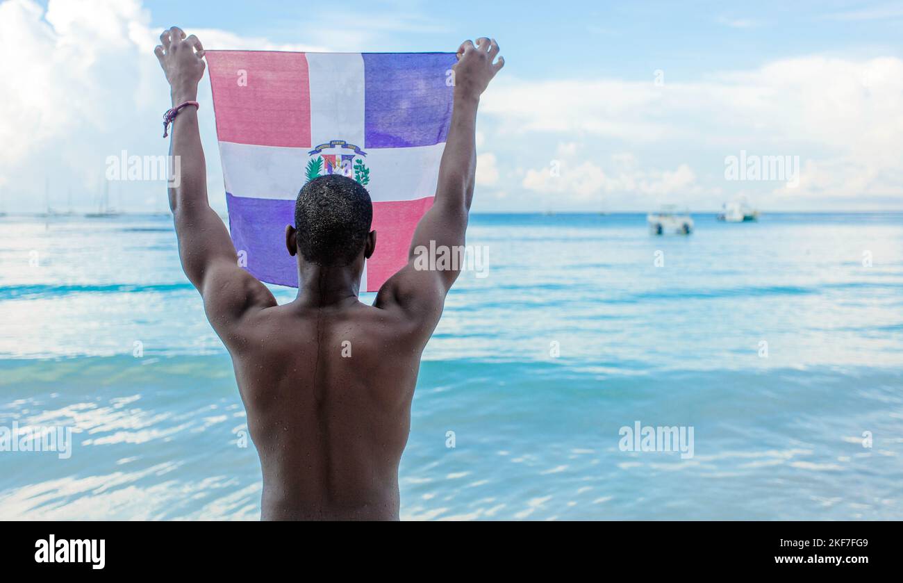 African American male from behind raising the flag of Dominican ...