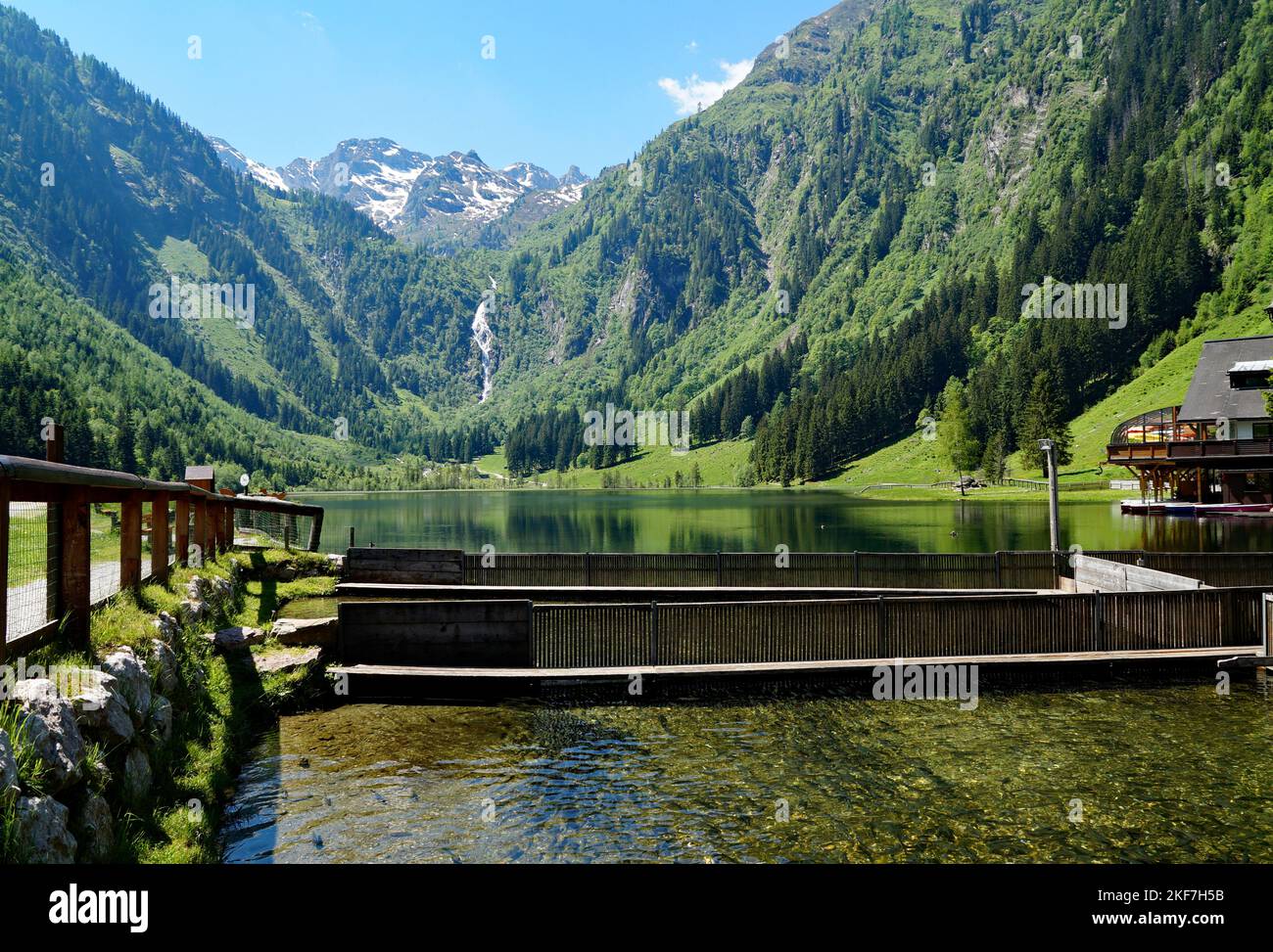 scenic alpine landscape with a waterfall, a transparent alpine lake and ...