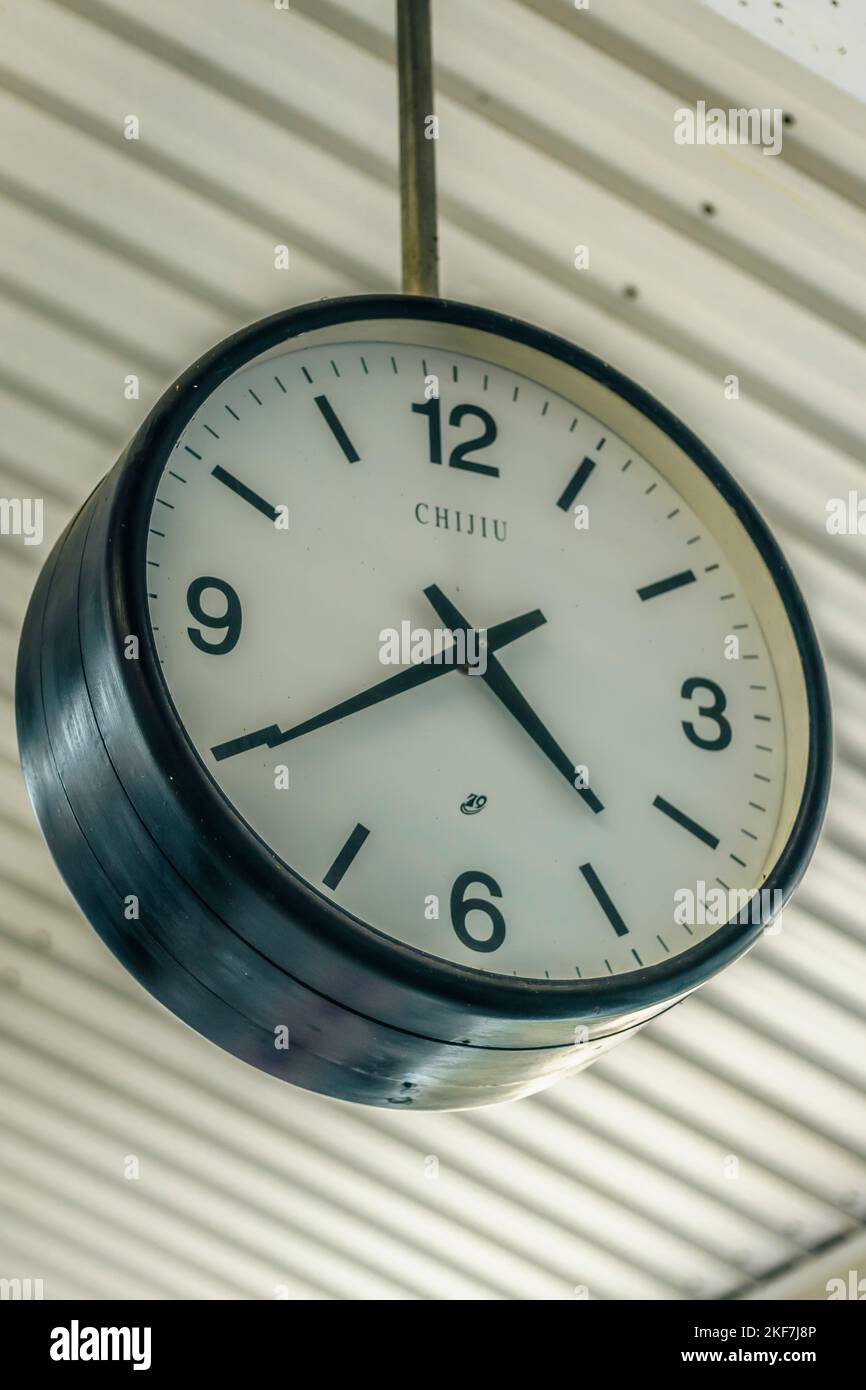 A vertical closeup low angle shot of a clock hung from the striped ...