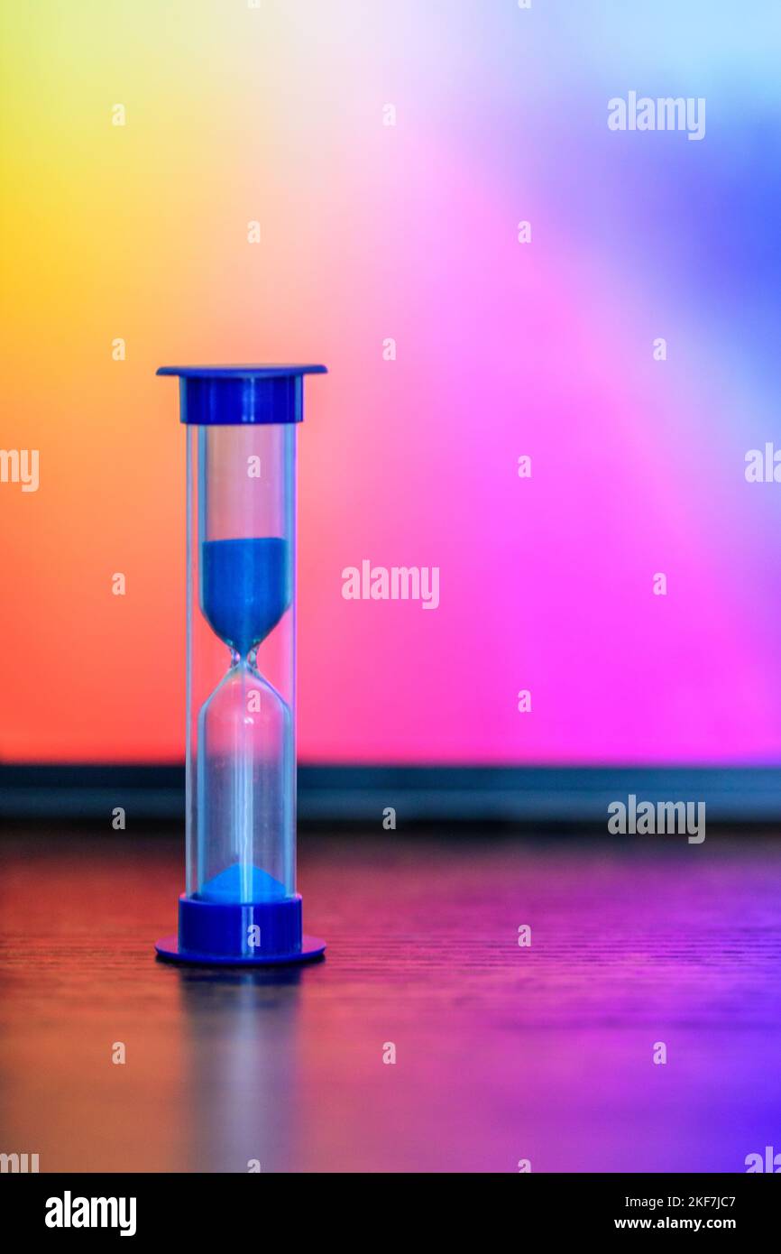 A vertical shot of a blue hourglass on a colorful background Stock ...