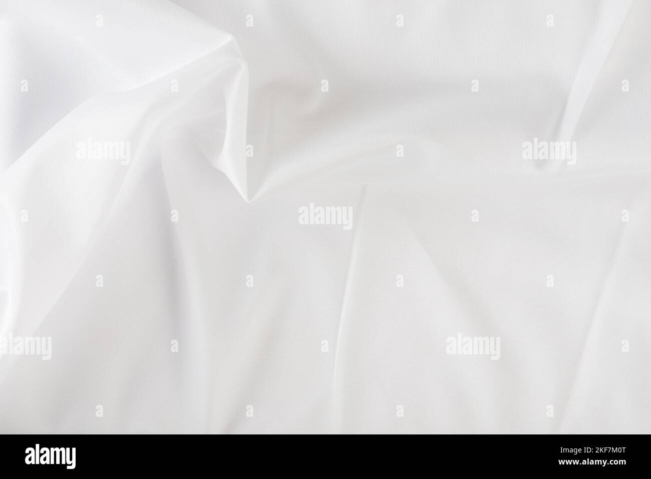 White wrinkled fabric. White fabric with large folds top view. For ...