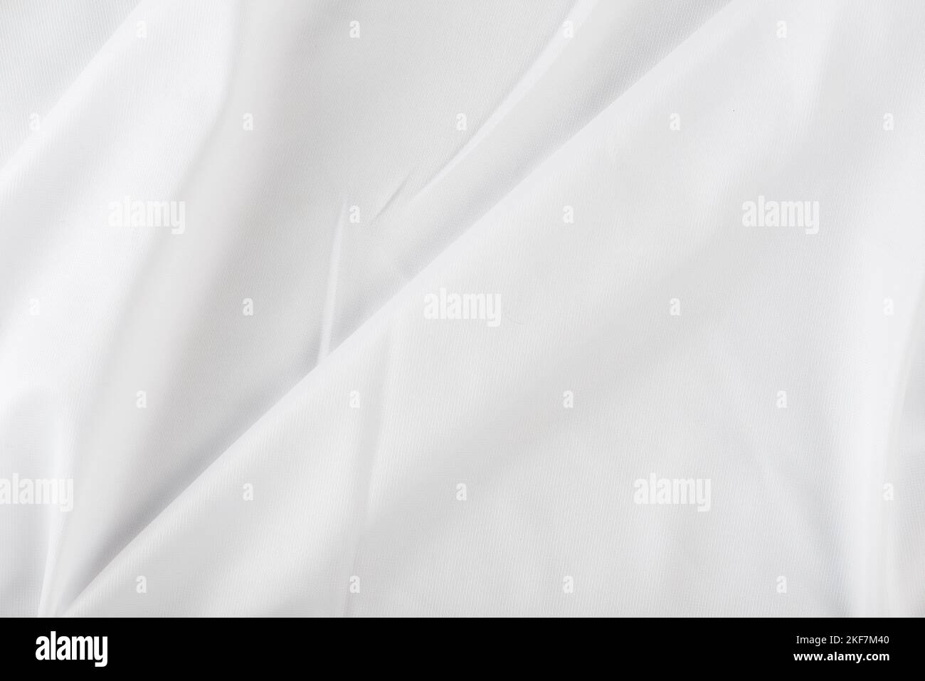 White wrinkled fabric. White fabric with large folds top view. For ...