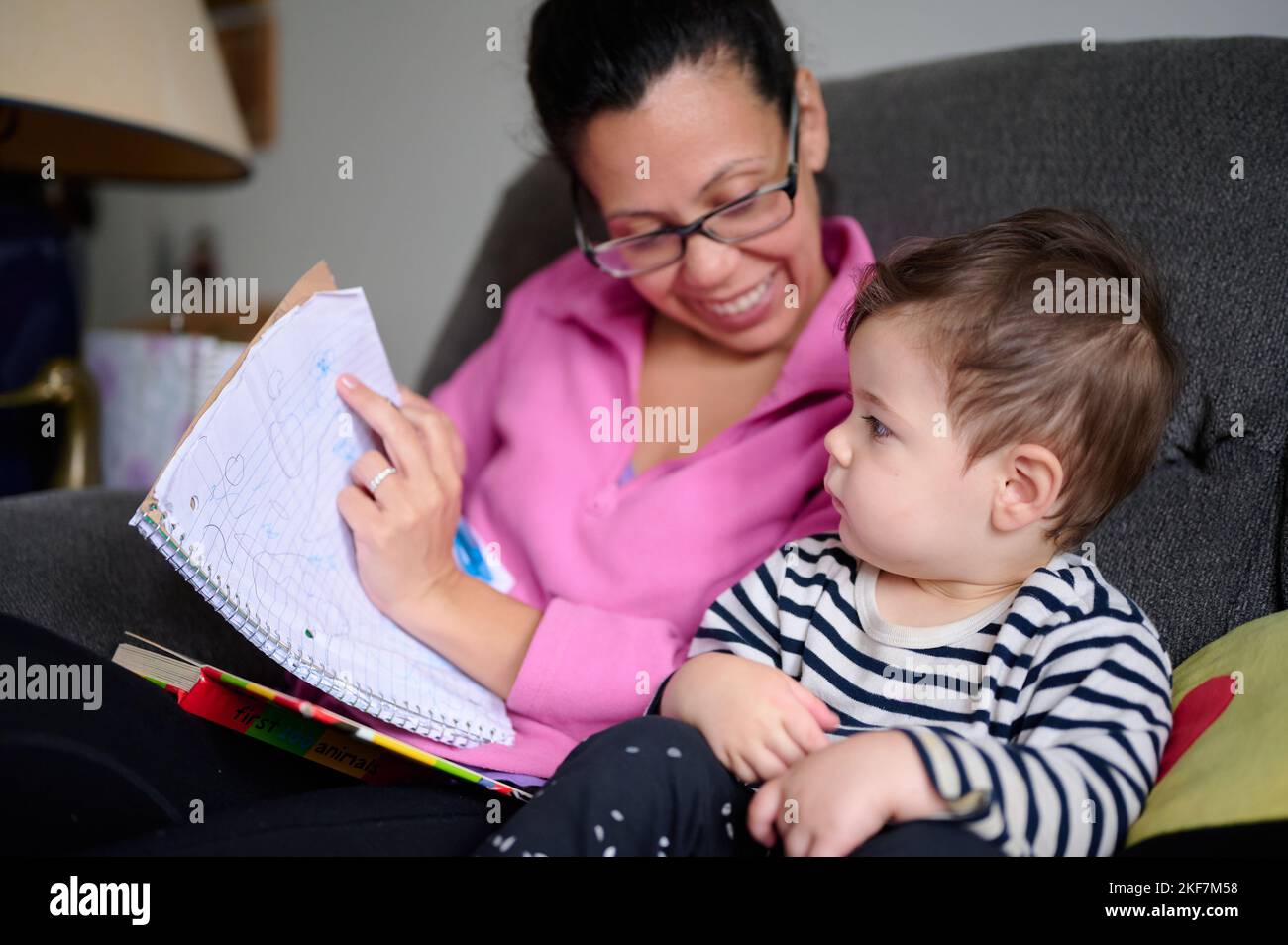 mom reading and writing with a cute toddler on the couch at home Stock ...