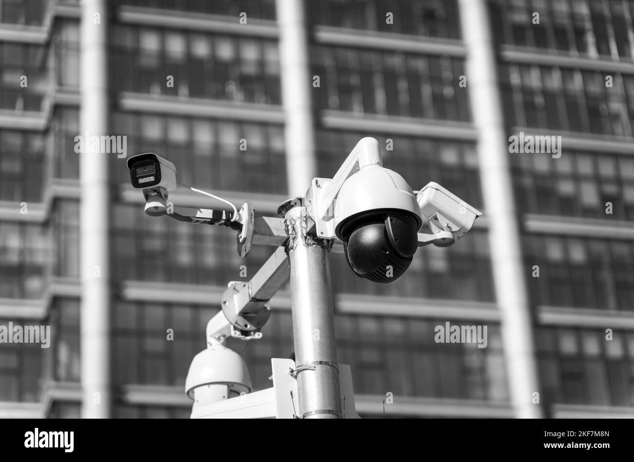 A black and white closeup of outdoor network cameras with a building on ...