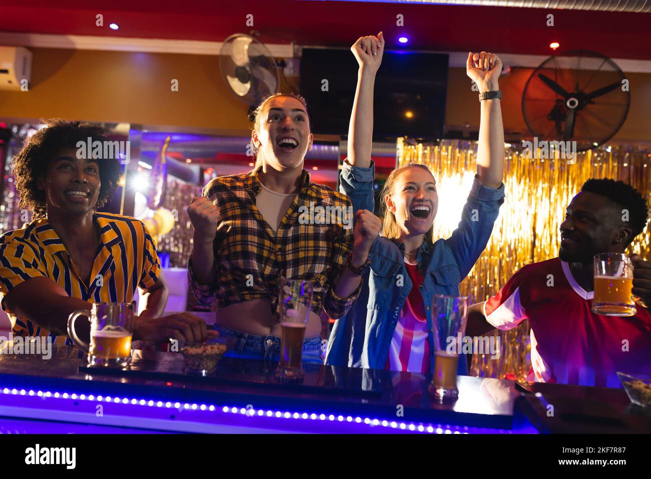 Diverse group of excited male and female friends watching sports game ...