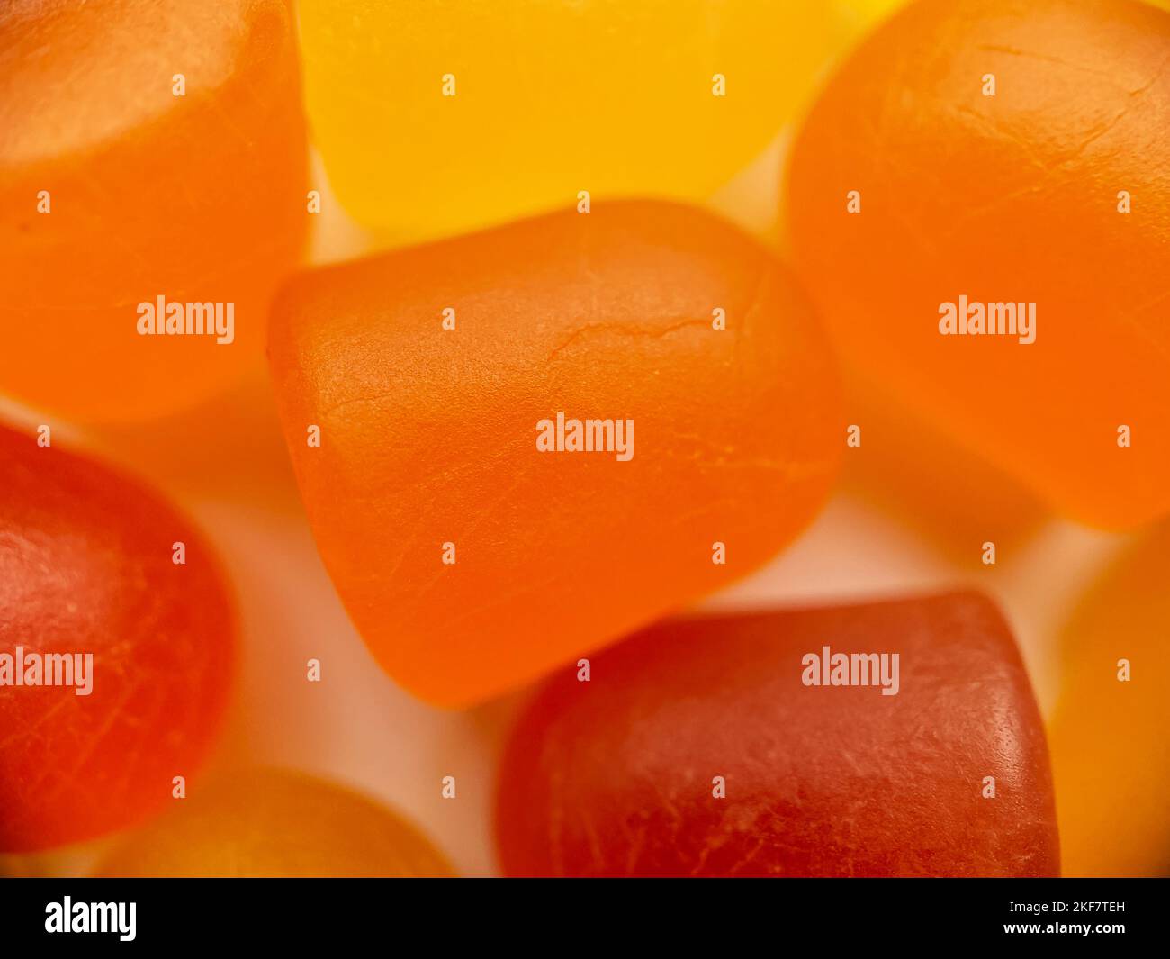 Close-up texture of orange and yellow multivitamin gummies on white ...