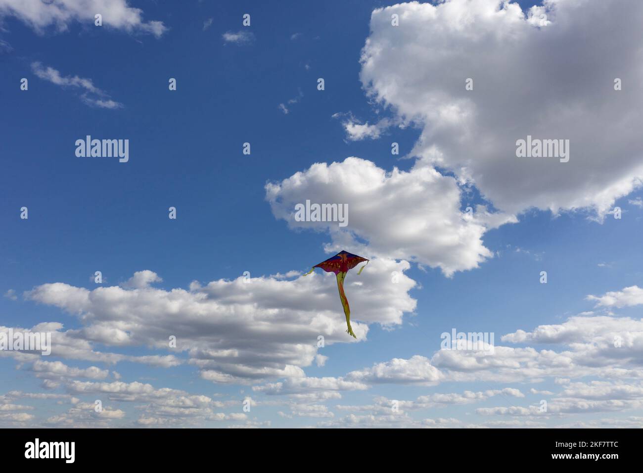 A kite flying in a blue cloudy sky Stock Photo - Alamy