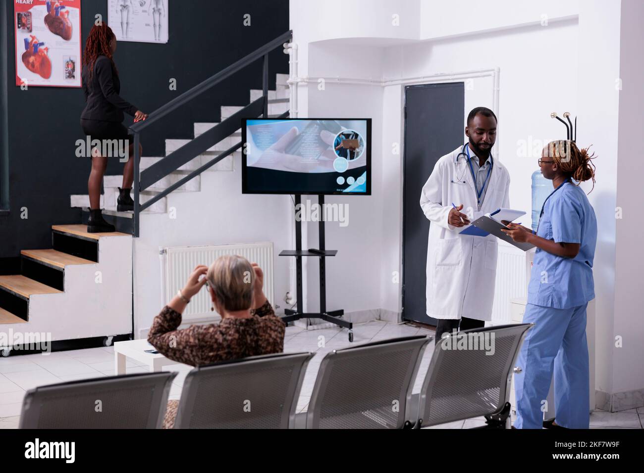 Clinical staff standing in hospital reception discussing patient disease symptoms while planning ...