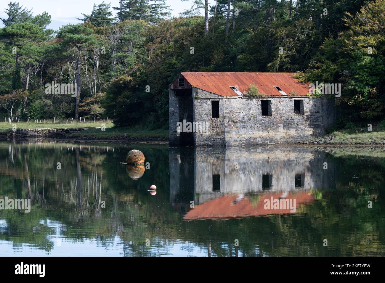 Perfect reflection of an old boat house at Westport Harbour, country ...