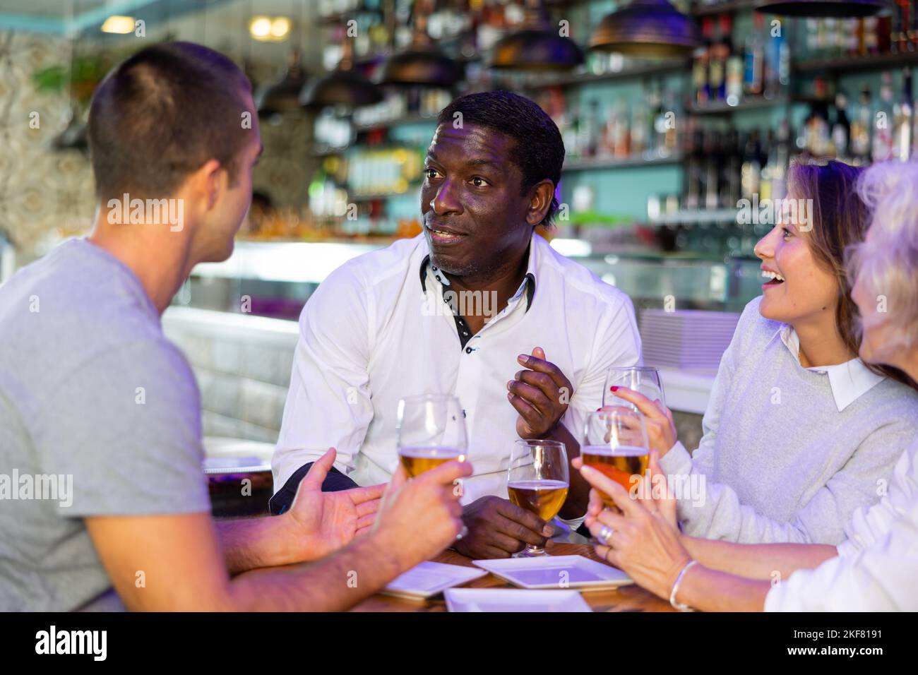 Spending time in bar. Four positive friends drinking beer Stock Photo ...