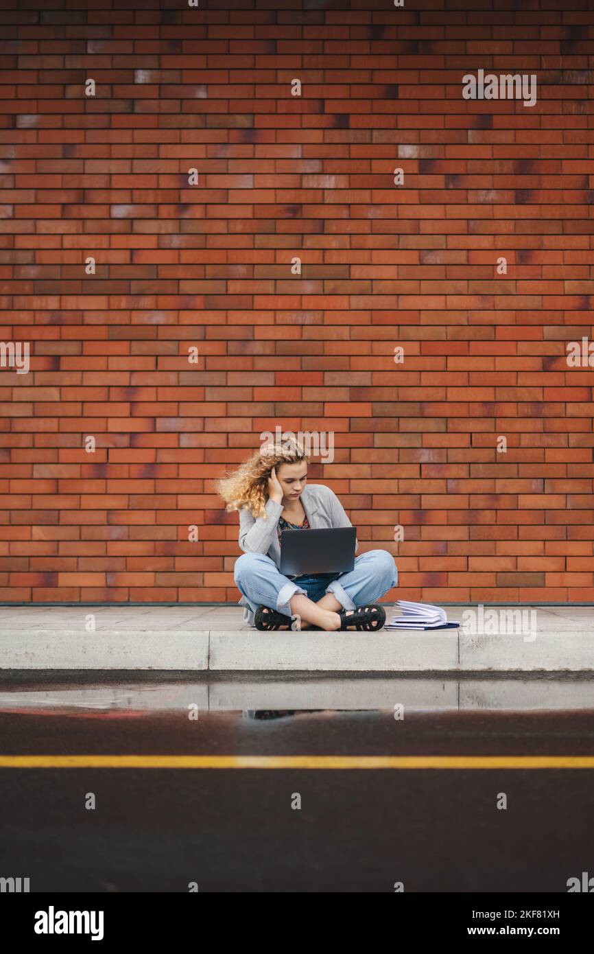 Beautiful young caucasian woman sitting on floor and working on laptop ...