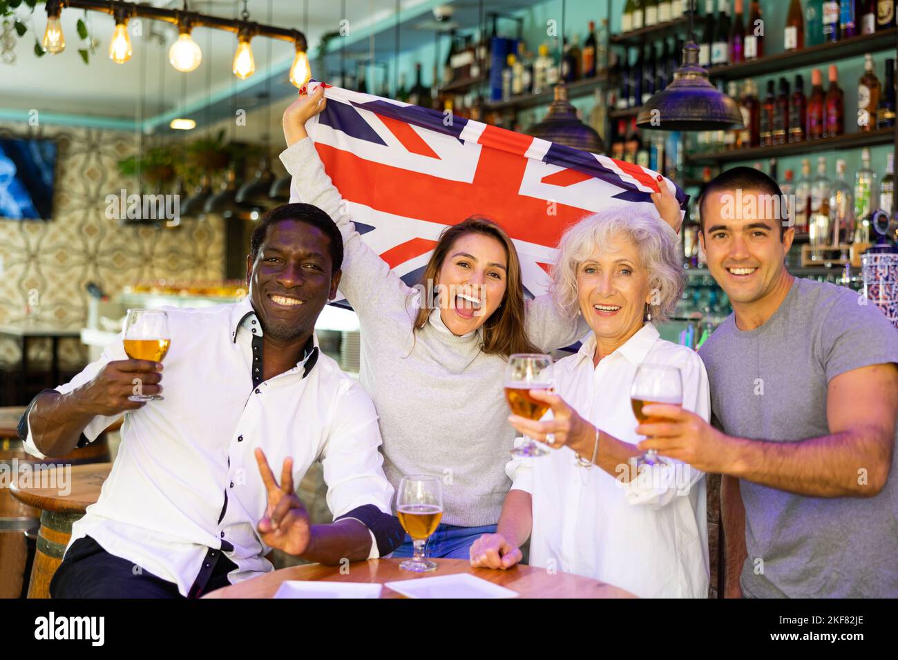 Happy multiracial friends holding the flag of England, rejoicing ...