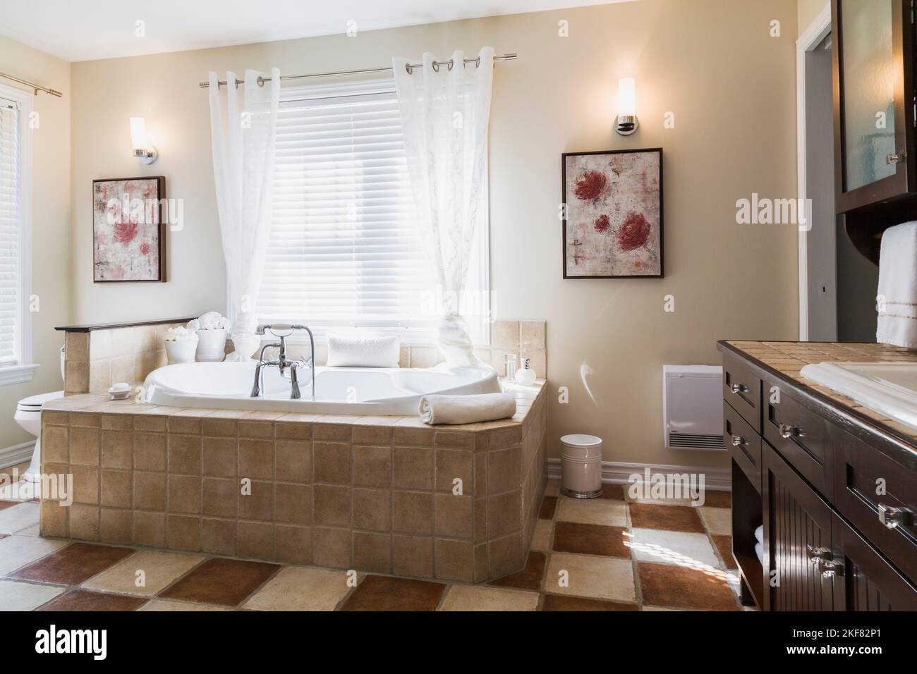Soaking tub encased in a brown and tan ceramic base and wooden vanity ...