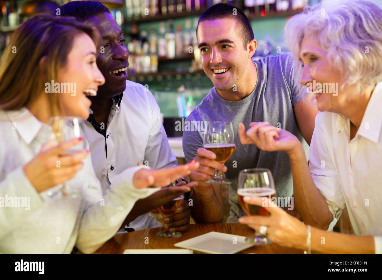 Diverse people talking and laughing drinking beer at a bar table Stock ...