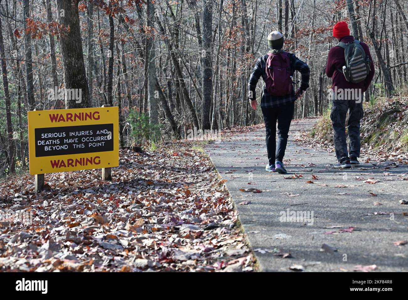 Two hikers walk past a warning sign at Hanging Rock State Park in North ...