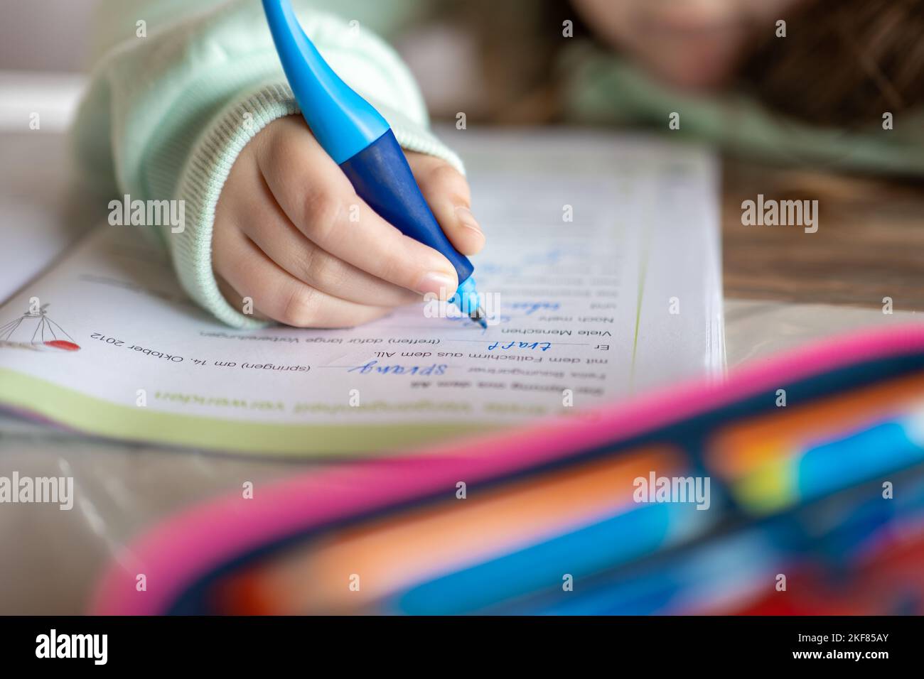 Homework.Girl writes words in a notebook.Schild writes with a pencil in ...