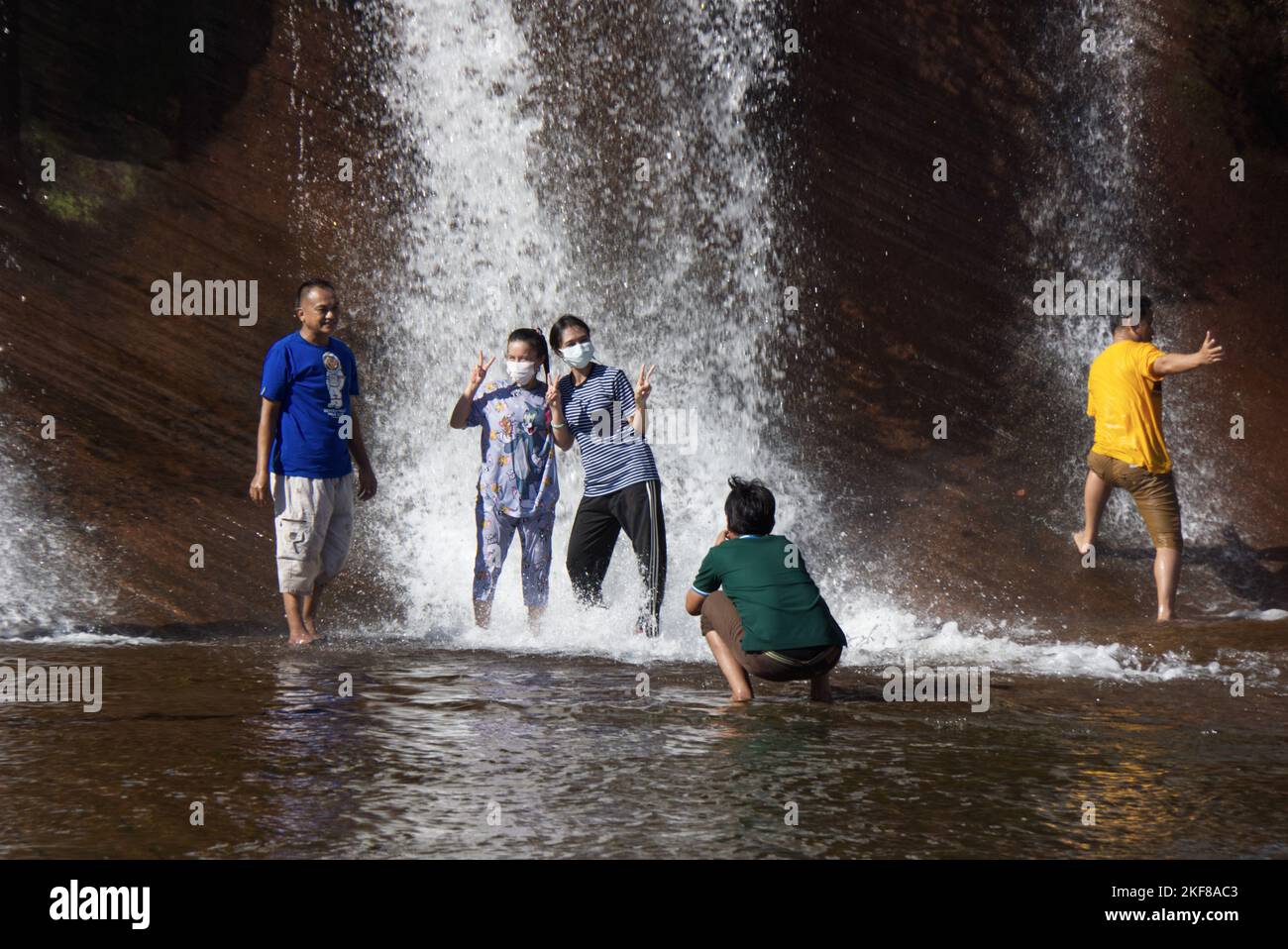 A group of people having fun and wearing masks while in a waterfall ...