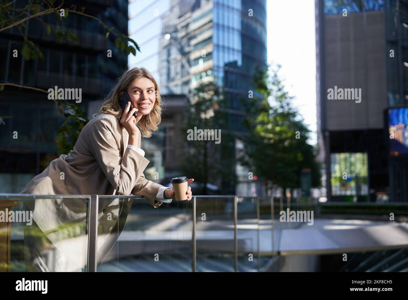 Happy smiling saleswoman stands on street on coffee break, talking on ...