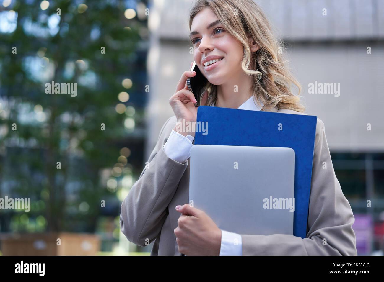 Smiling professional businesswoman talking on mobile phone, holding ...