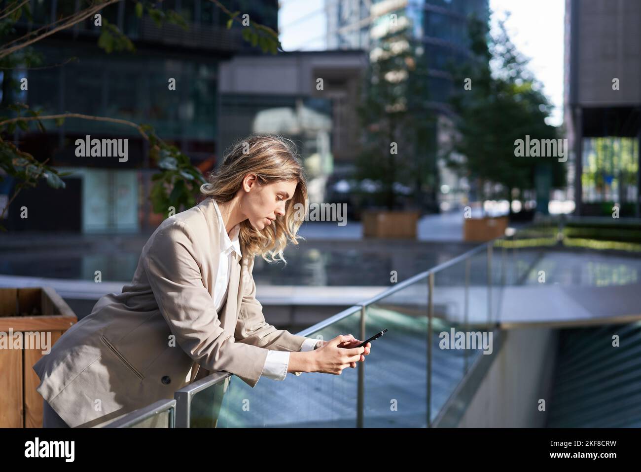 Corporate woman using mobile phone. Businesswoman standing outdoors ...